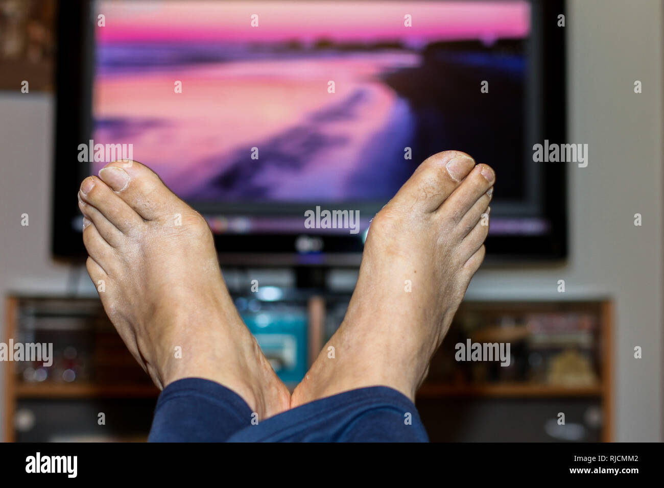 Man legs with beach sunset on tv screen Stock Photo - Alamy