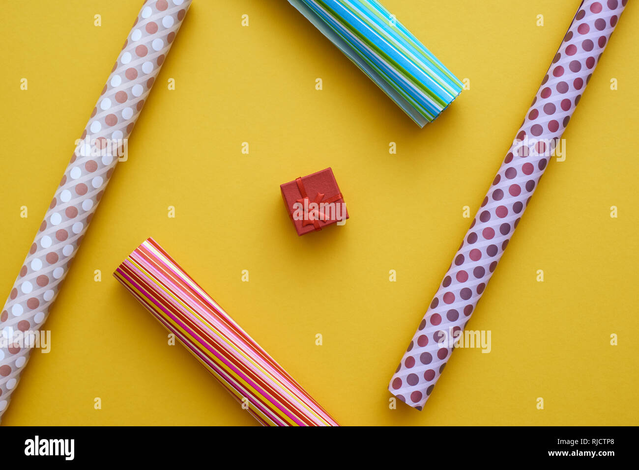 Easy Gift Packing. Small gift box and colorful wrapping paper on yellow ...