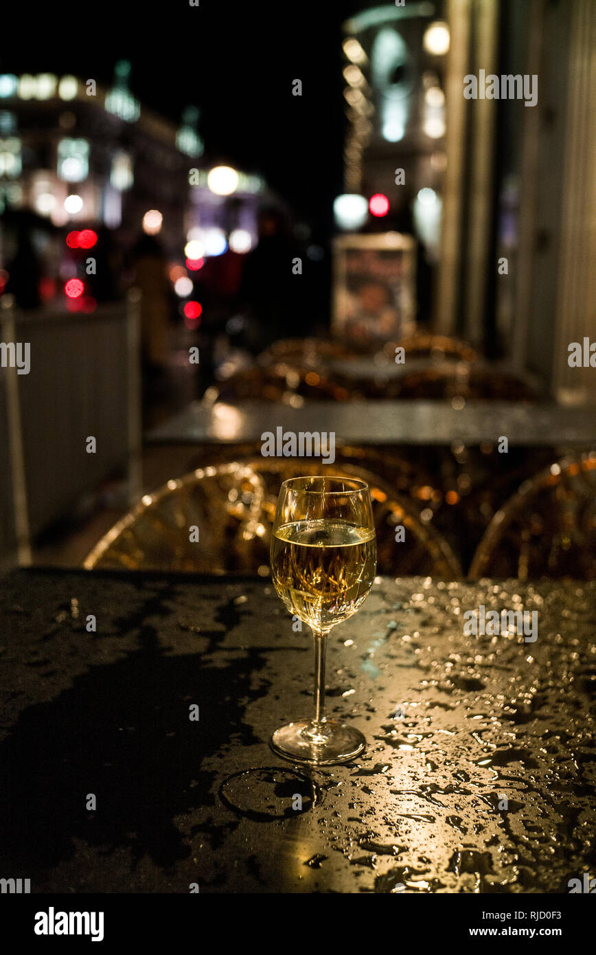 wine glass on rain drenched roadside table at night in the city Stock ...