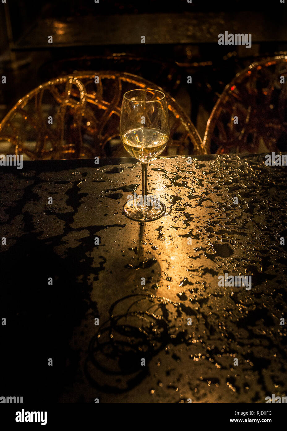 wine glass on rain drenched roadside table at night in the city Stock ...