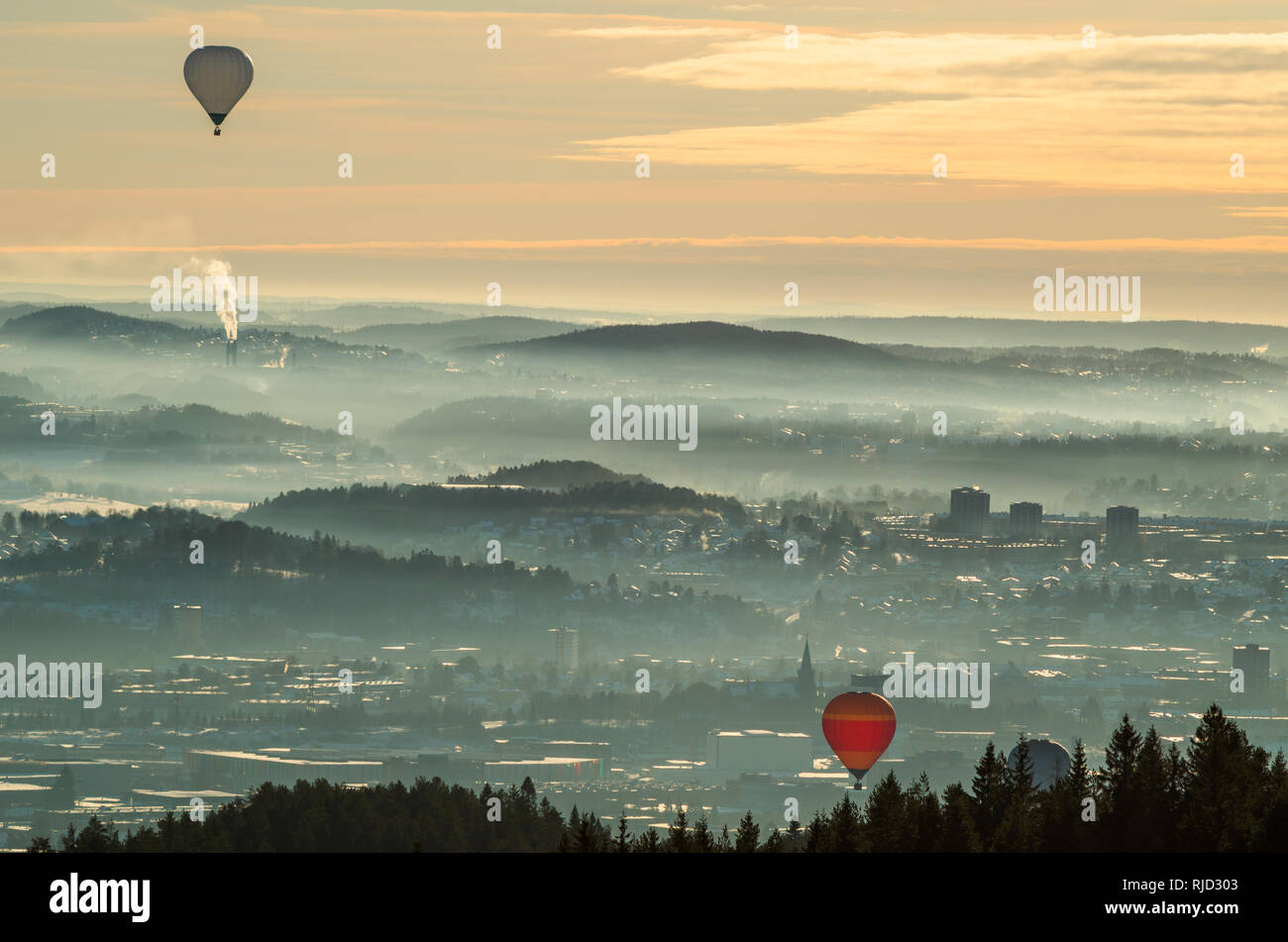 Hot air baloons flying over Oslo hidden in smog or fog in winter calm ...