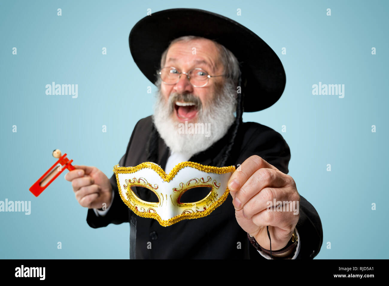 Portrait of a senior orthodox Hasdim Jewish man with wooden Grager ...