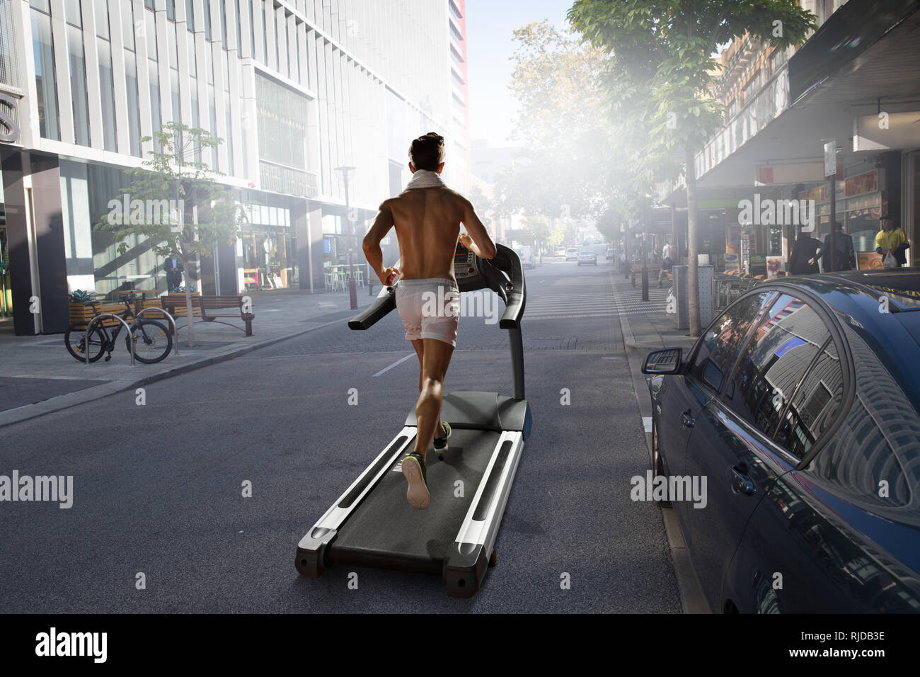 Back view of man athlete running on treadmill. Mixed media Stock Photo ...