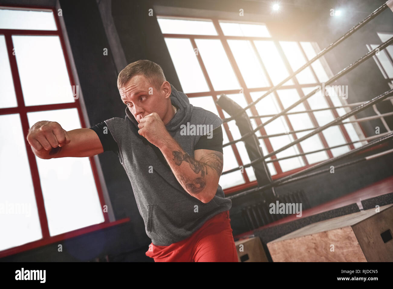 Confident handsome athlete in sports clothing performing side punch ...
