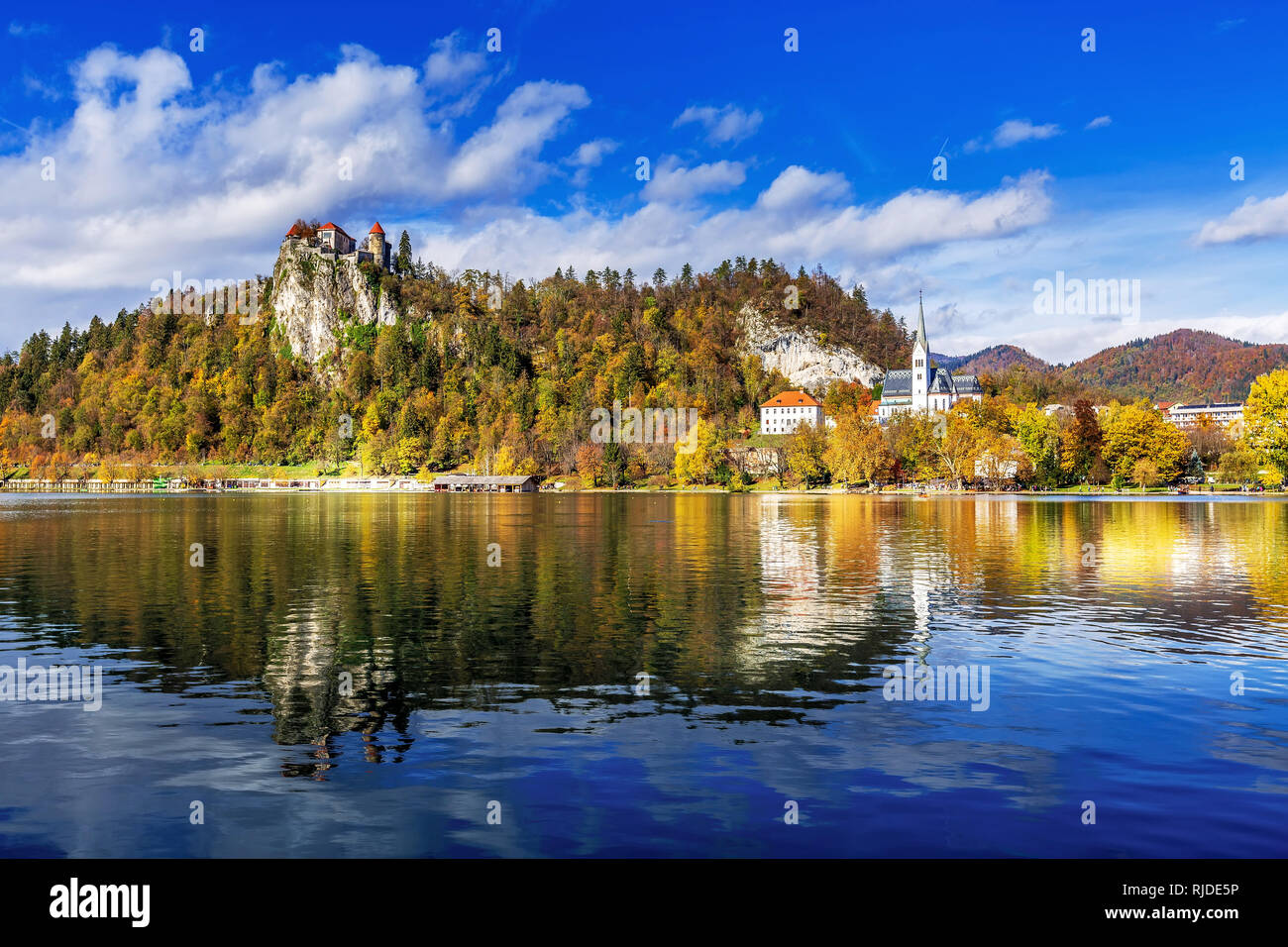 Medieval castle on rock top at Bled lake in Slovenia and autumn trees ...