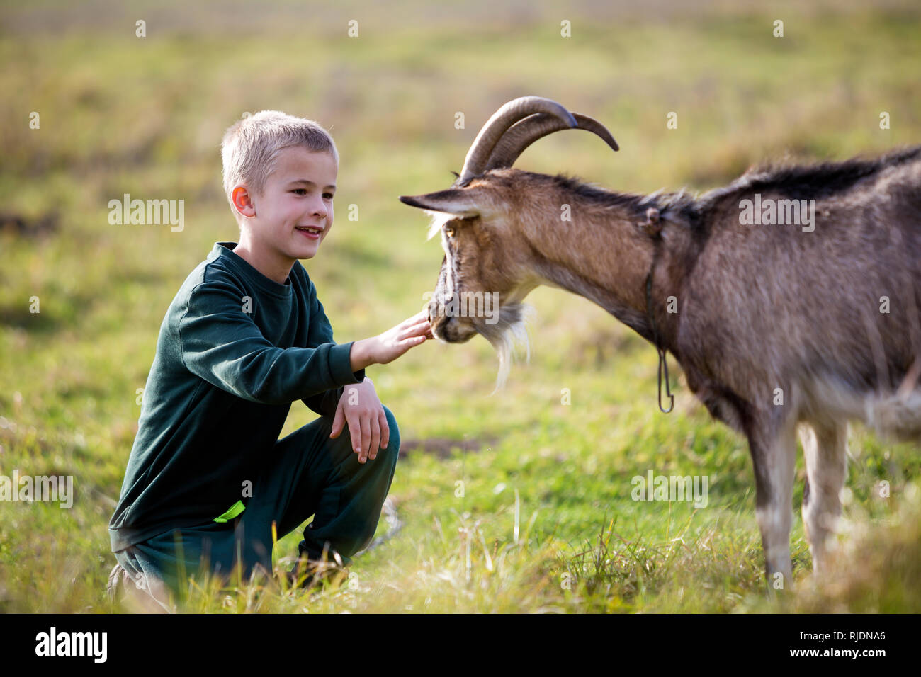 Young blond cute handsome smiling child boy playing with horned bearded ...