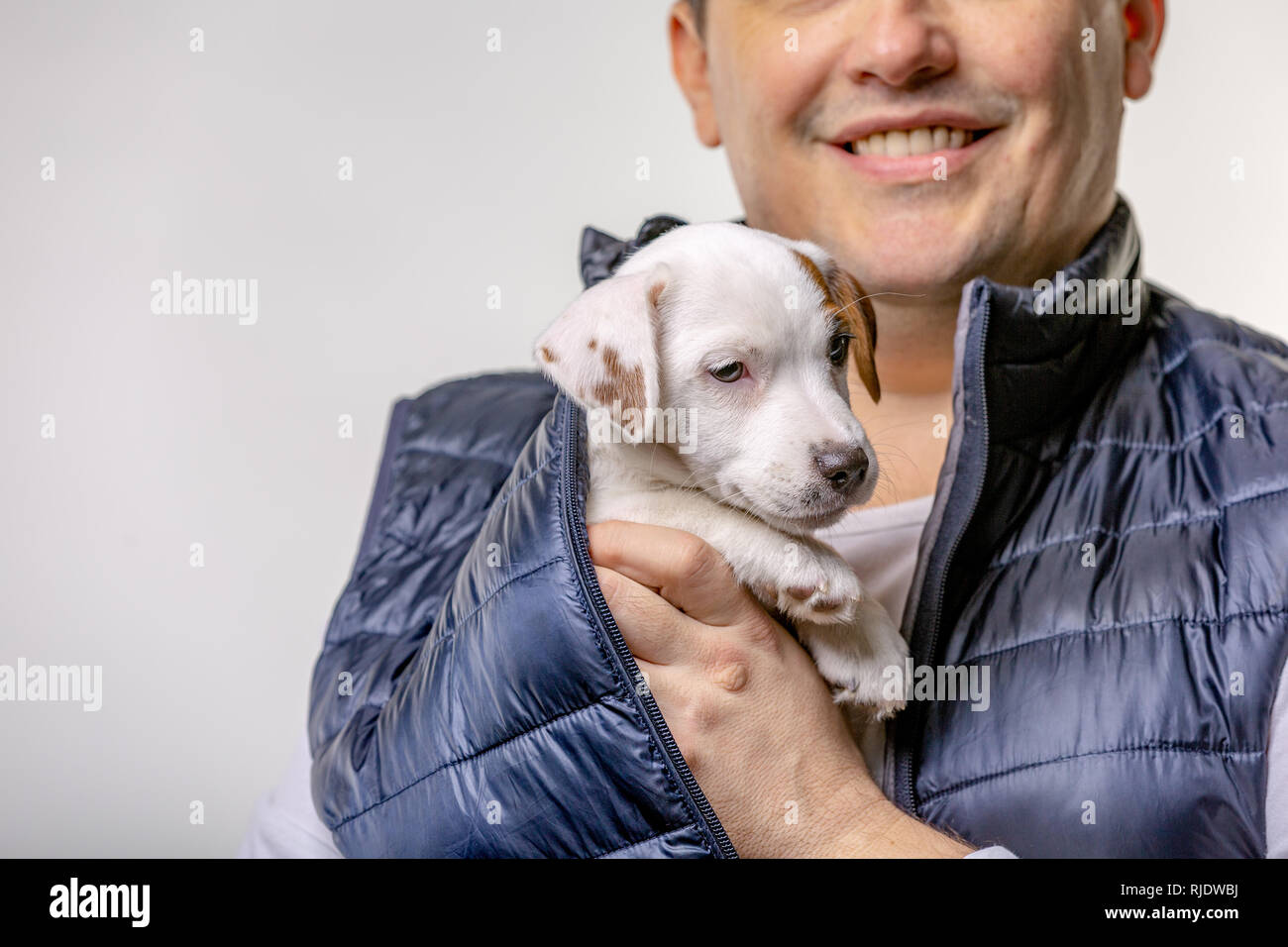 Horizontal portrait of handsome cheerful man holds jack russell ...