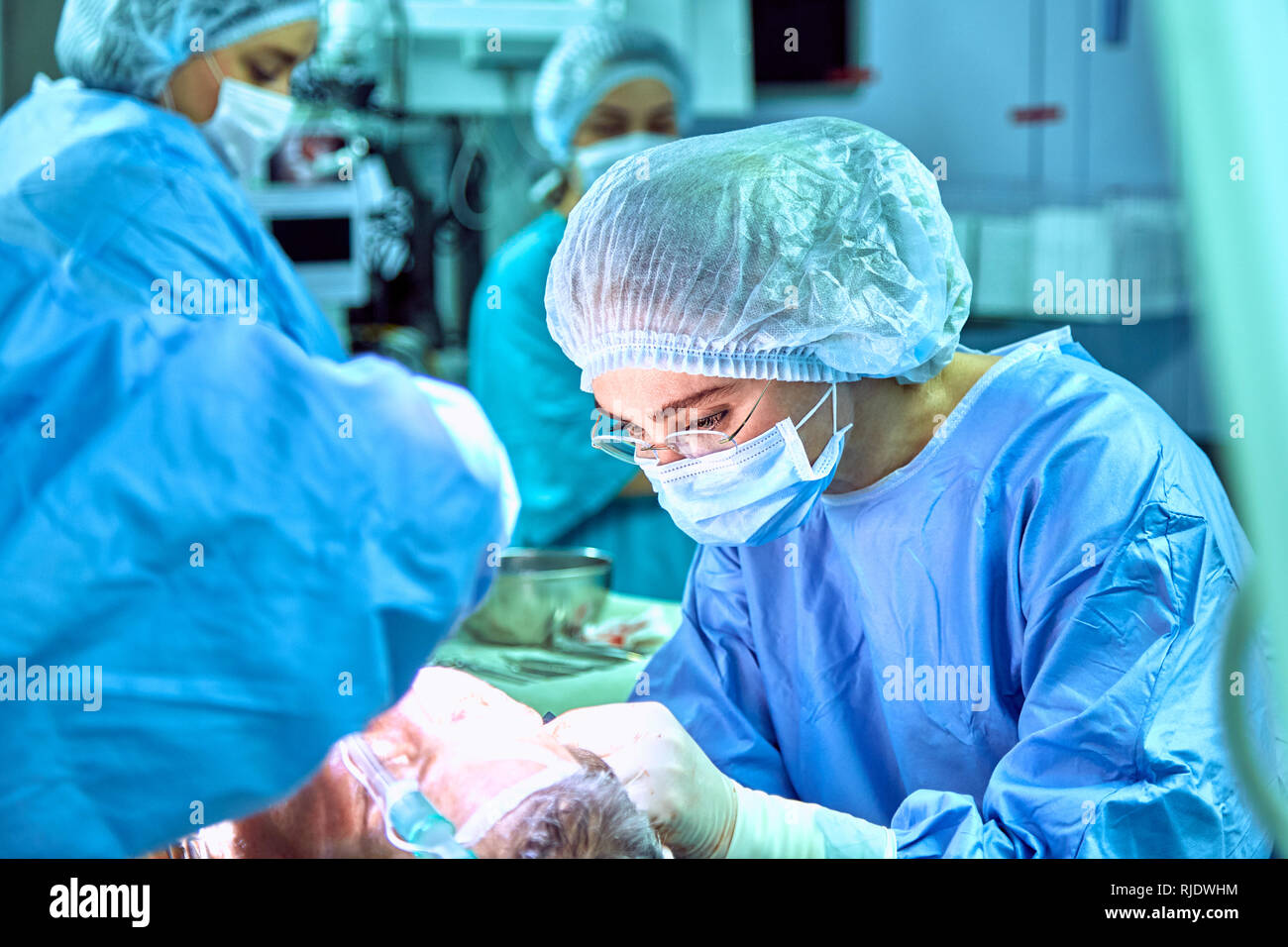 Several surgeons surrounding patient on operation table during their ...