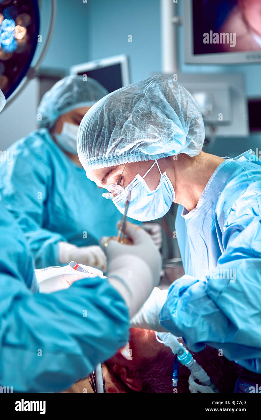 Several surgeons surrounding patient on operation table during their ...