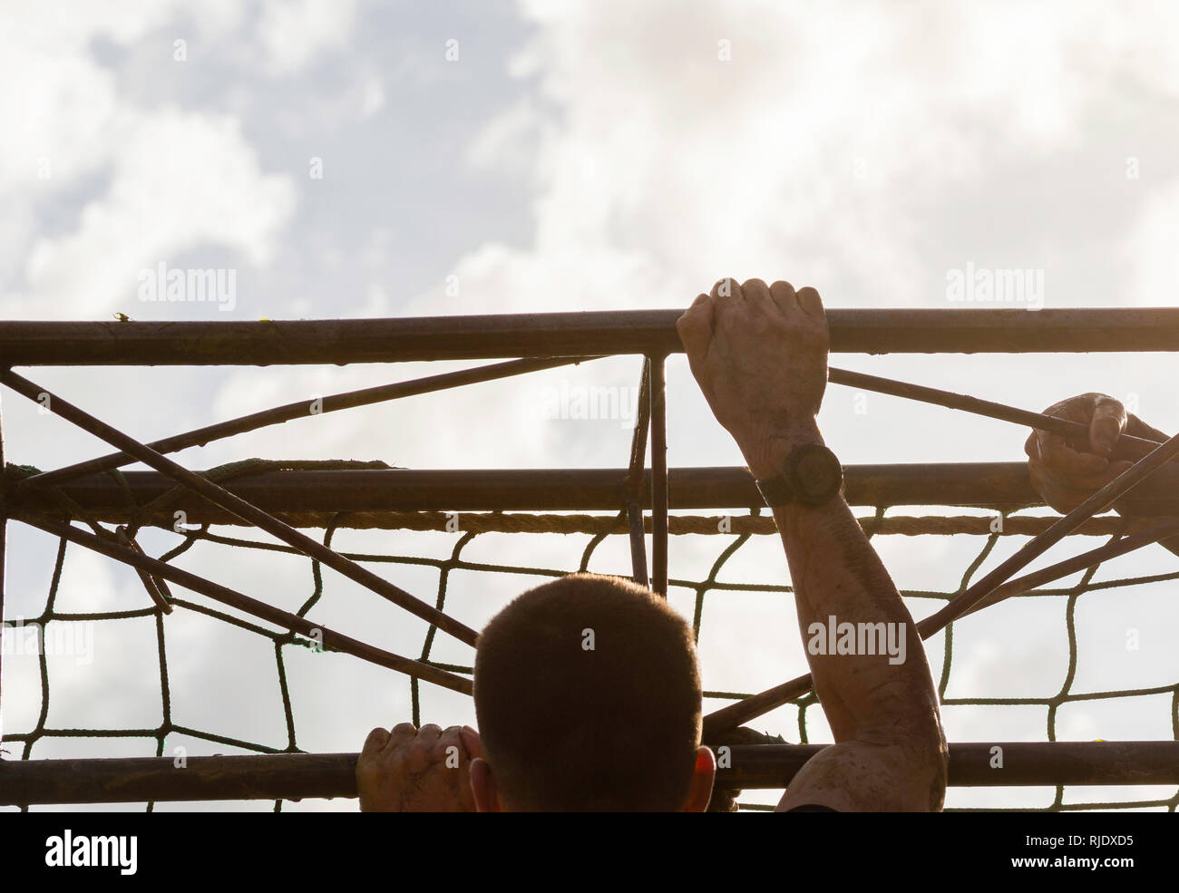 Mud race runners, defeating obstacles by using ropes. Details of the ...