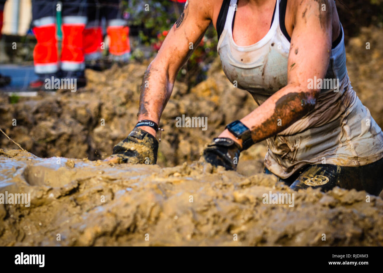 Mud race runners, defeating obstacles by using ropes. Details of the ...