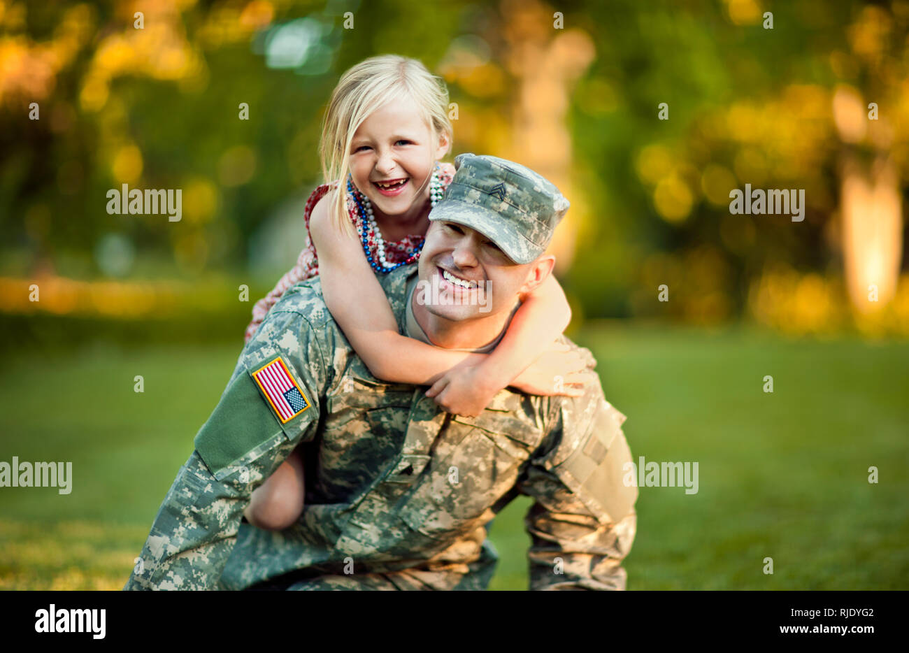 Portrait of a smiling army soldier giving his young daughter a piggy ...
