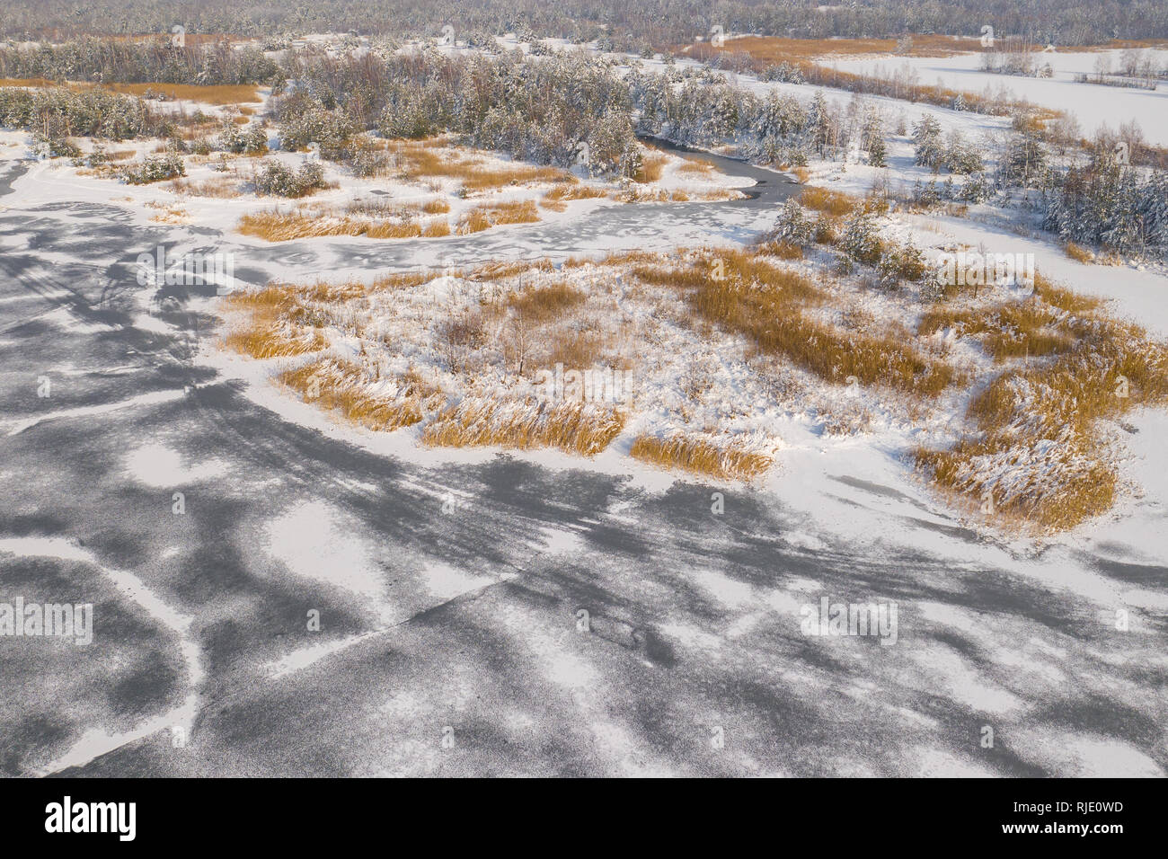 Aerial view of the winter snow covered forest and frozen lake from ...
