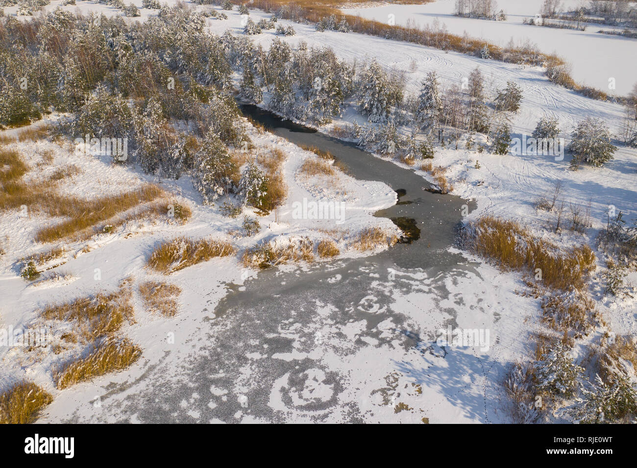 Aerial view of the winter snow covered forest and frozen lake from ...