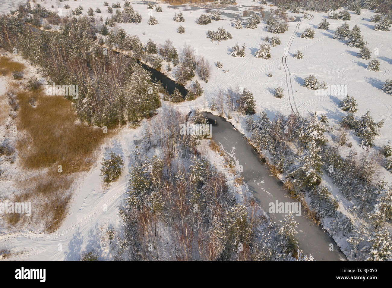 Aerial view of the winter snow covered forest and frozen lake from ...