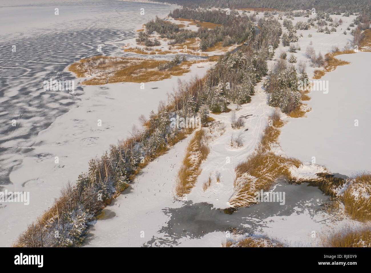 Aerial view of the winter snow covered forest and frozen lake from ...