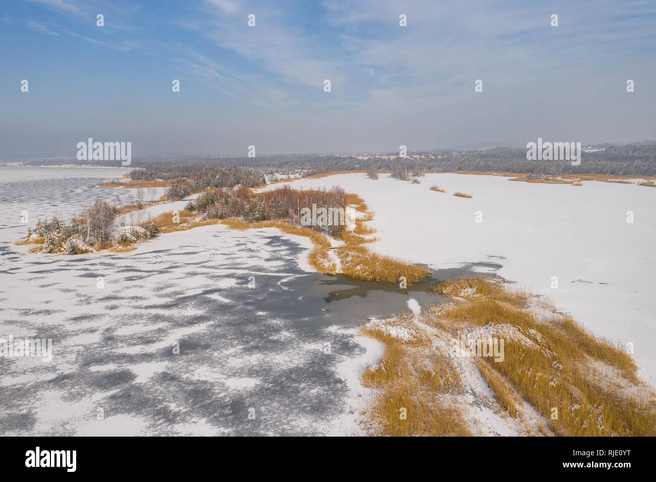 Aerial view of the winter snow covered forest and frozen lake from ...