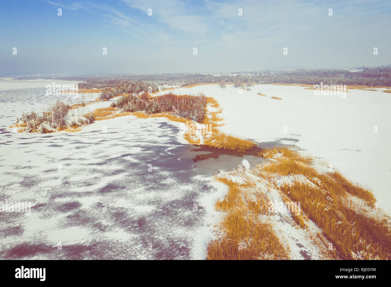 Aerial view of the winter snow covered forest and frozen lake from ...