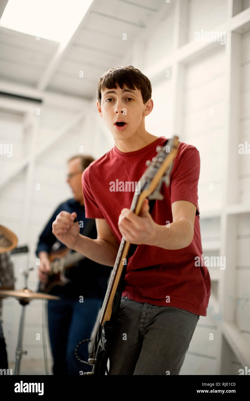 Teenage boy playing a bass guitar enthusiastically Stock Photo - Alamy