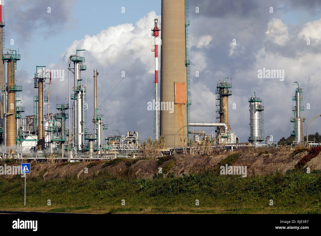 Part of a big oil refinery with red and white chimney in a cloudy ...