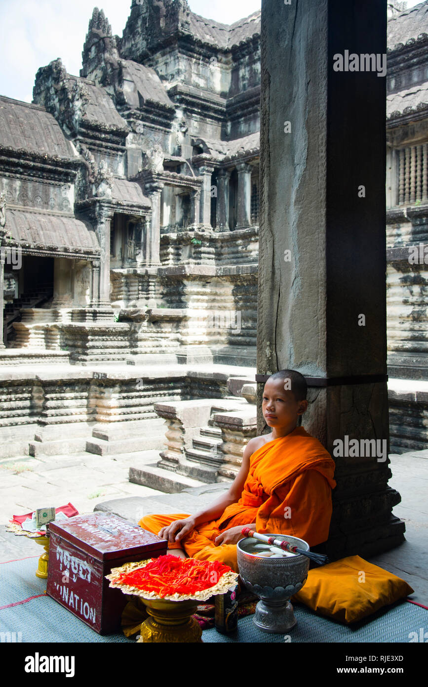 Young monk in saffron robe at Angkor Wat Buddhist temple ruins in Siem ...
