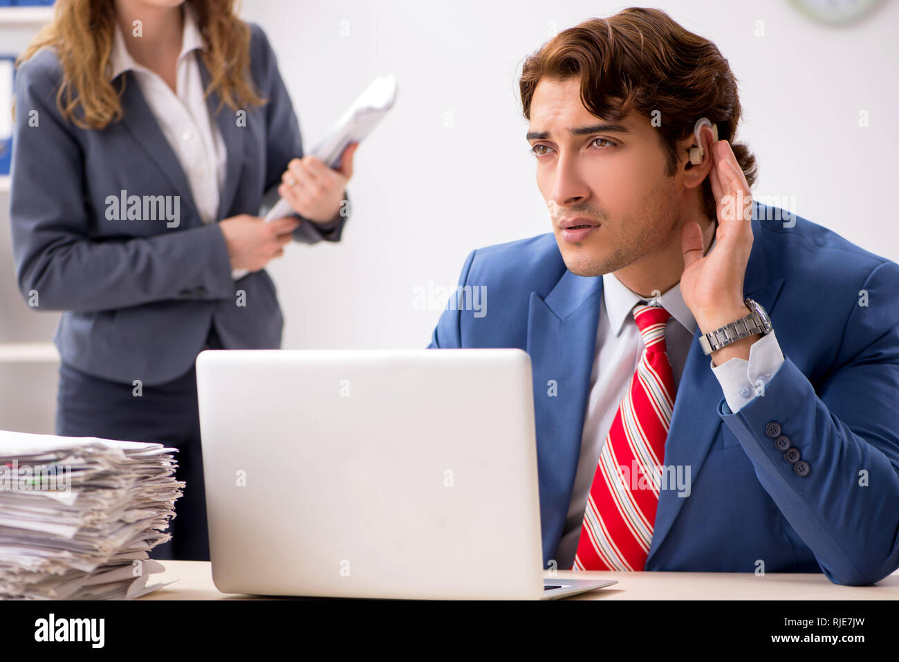 Deaf employee using hearing aid talking to boss Stock Photo - Alamy