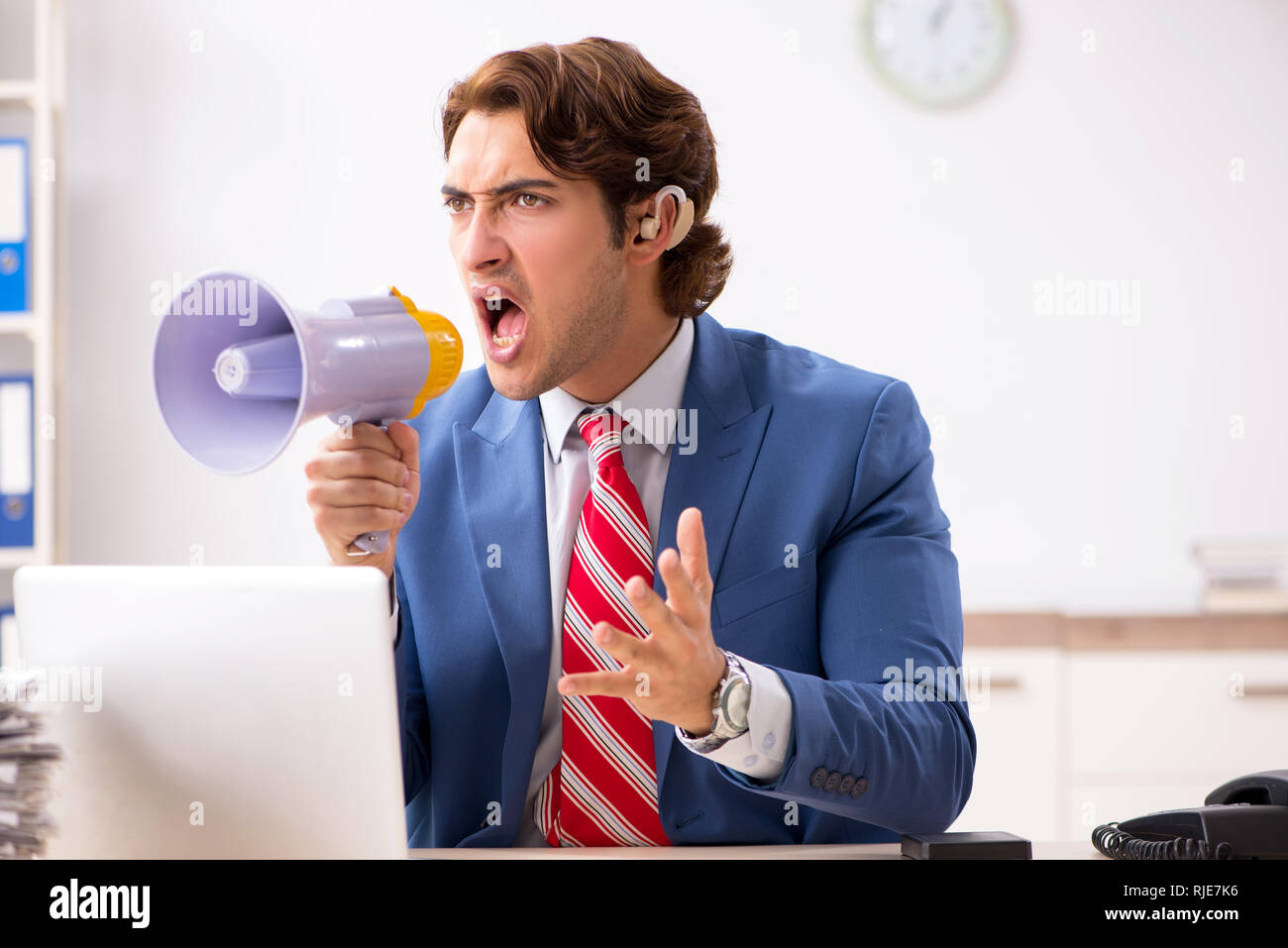 Deaf employee using hearing aid in office Stock Photo - Alamy