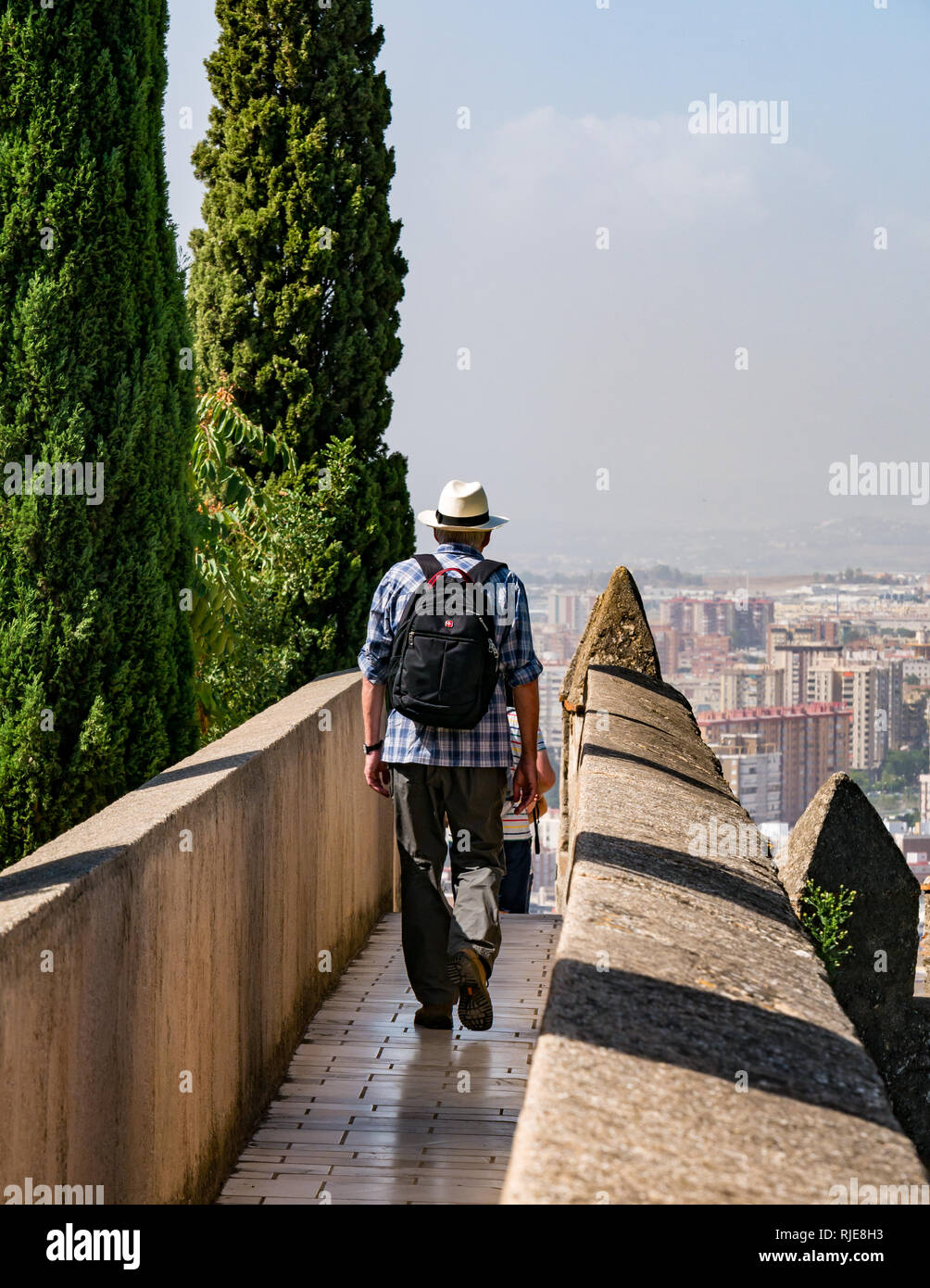 Senior man wearing Panama hat walking on outer fortified wall, Alcazaba ...