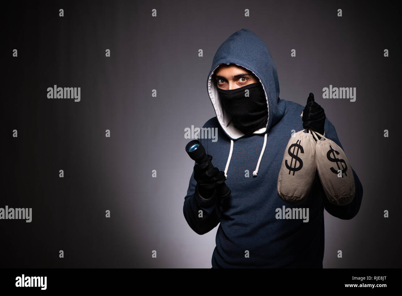 Young gangster in hood on grey background Stock Photo - Alamy