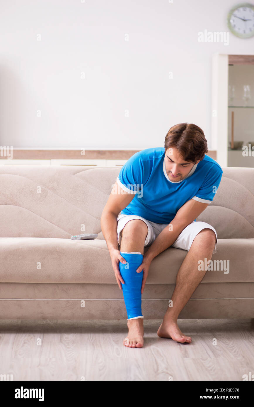 Leg injured young man on the sofa Stock Photo - Alamy