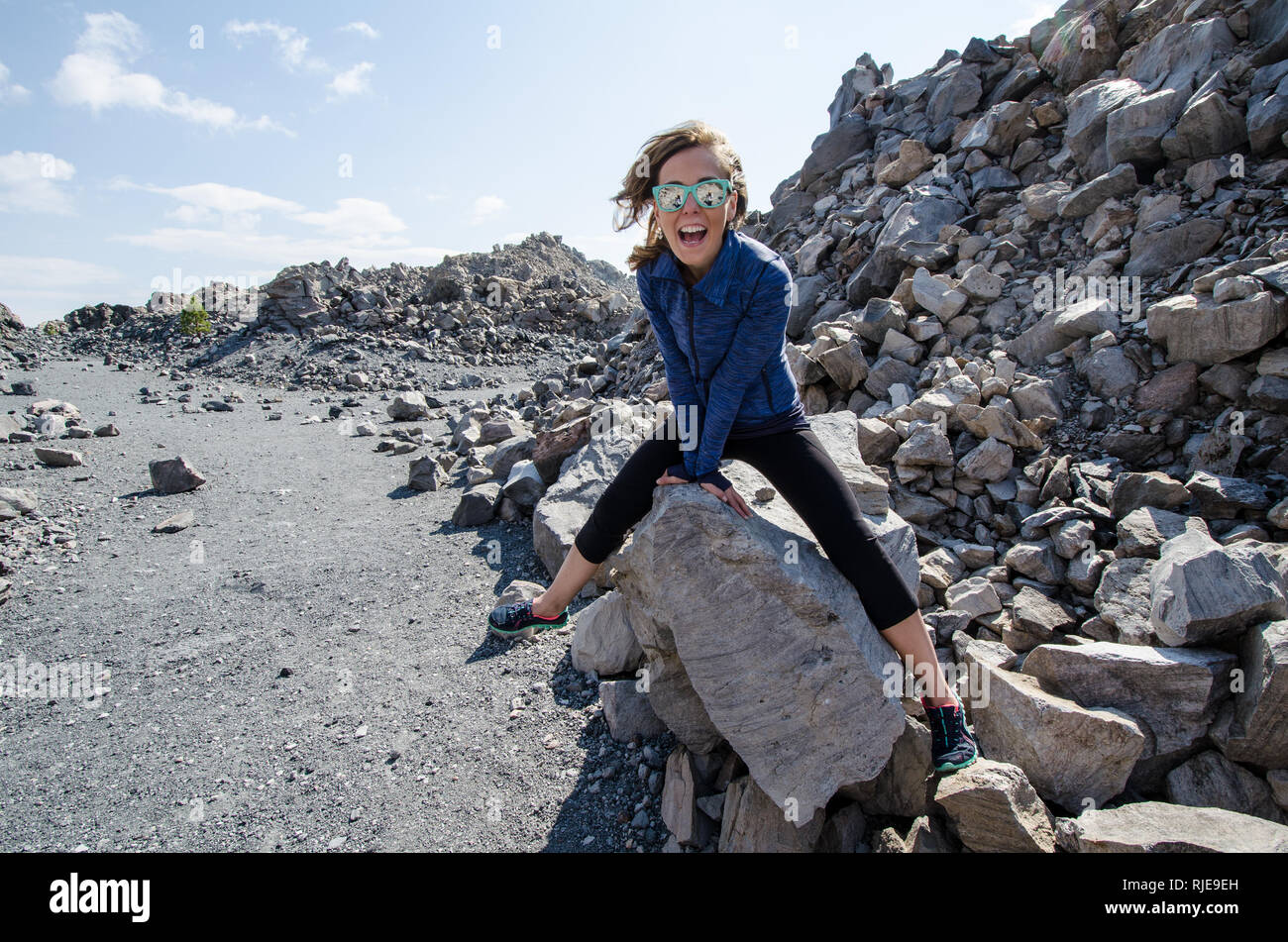 Adult woman straddles on rocks at the Obsidian Dome trail in California ...