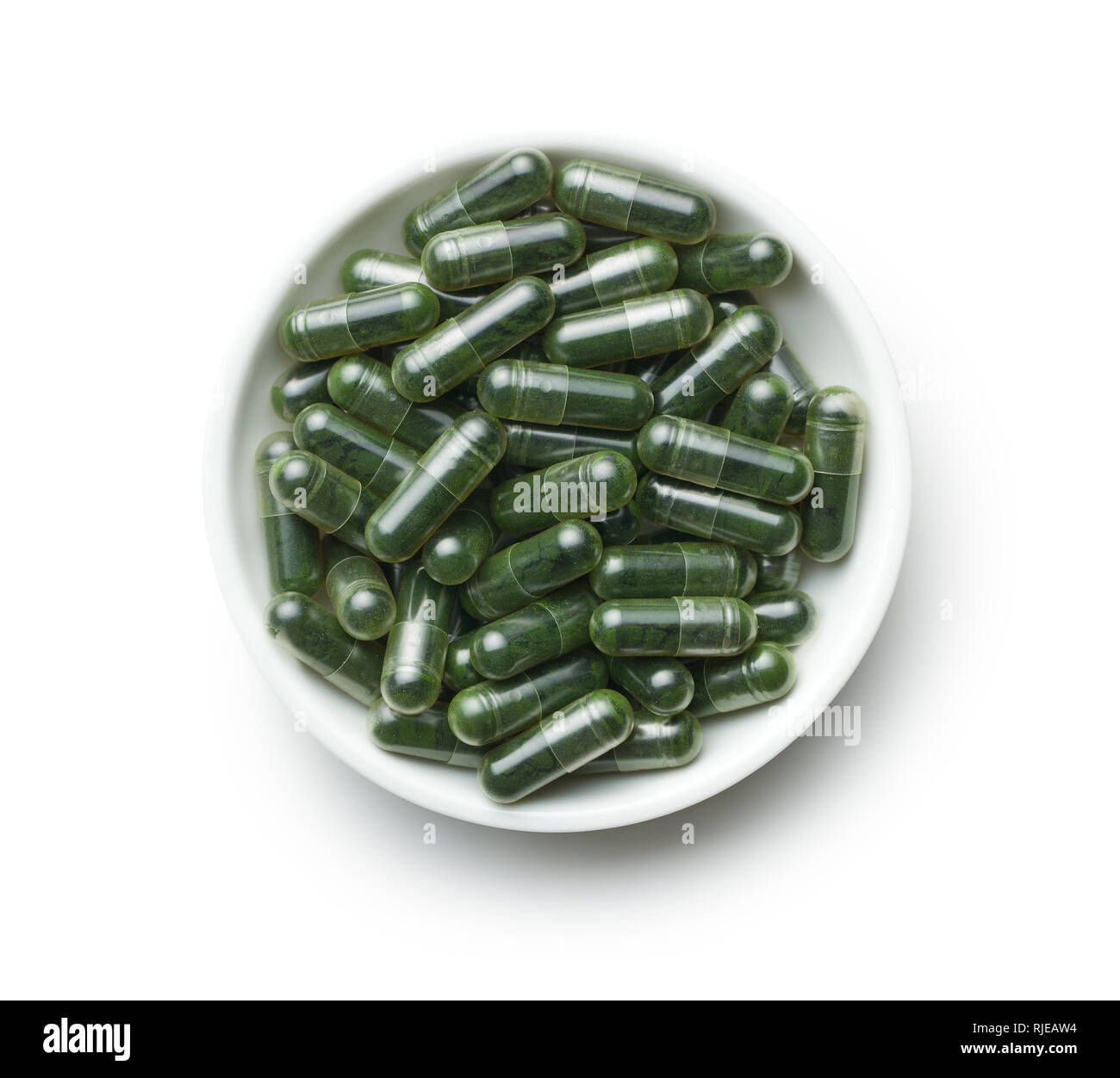 Green chlorella pills or green barley pills in bowl isolated on white ...