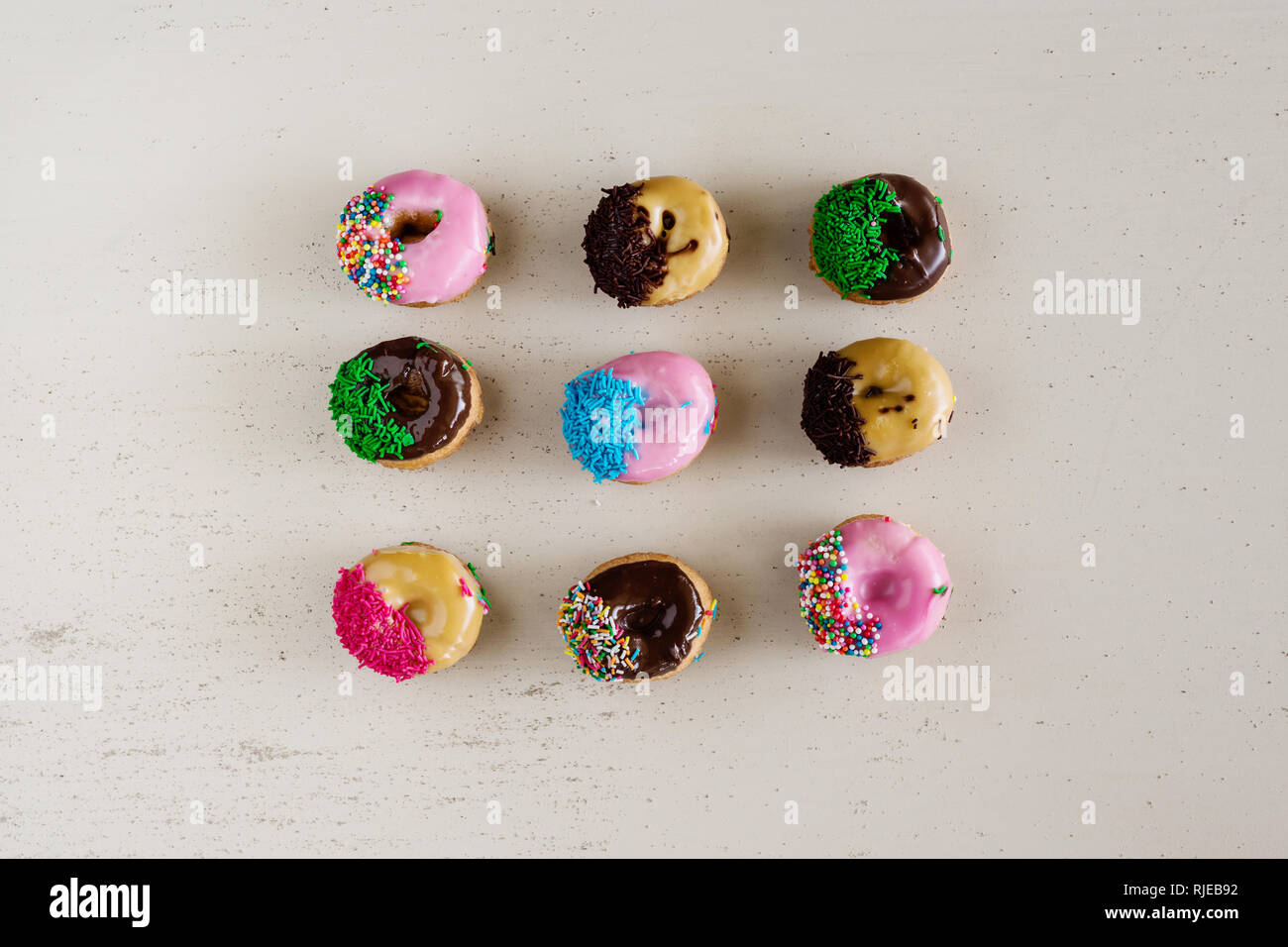 mini donuts in various colours on a plain background Stock Photo - Alamy