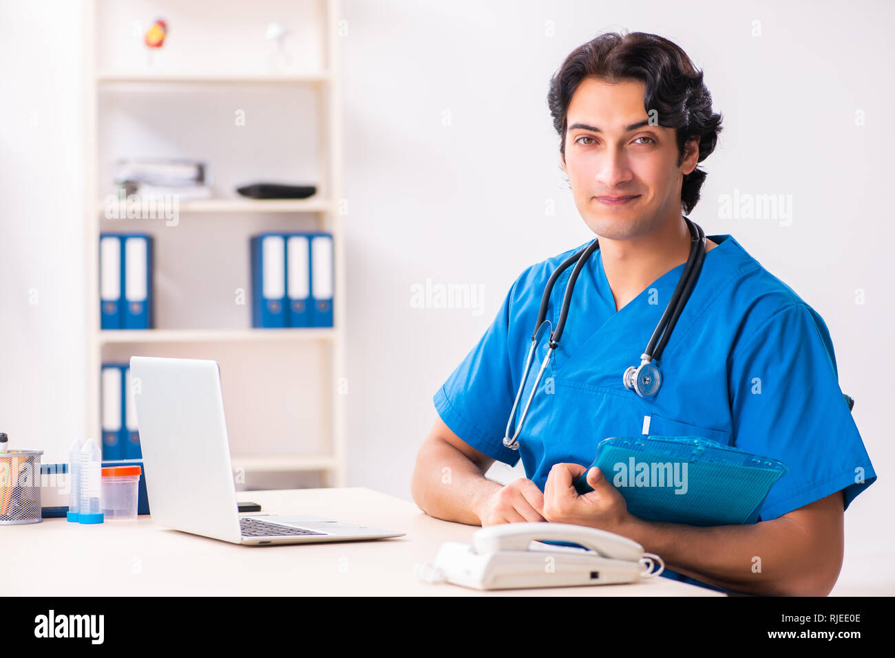 Young handsome doctor working at the clinic Stock Photo - Alamy