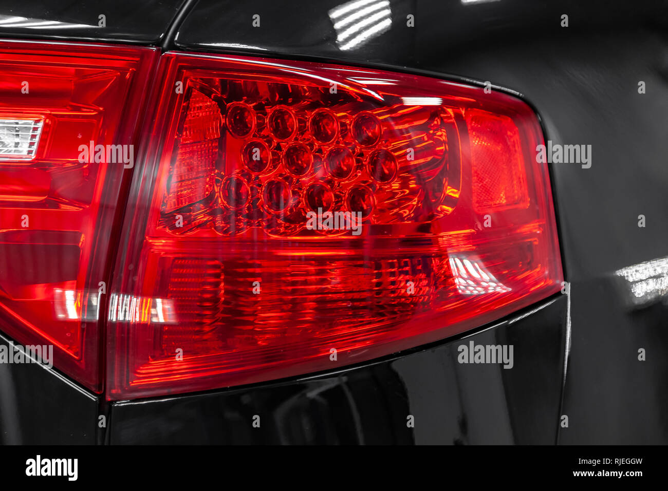 Close-up on the rear LED brake light of red color on a black car in the ...