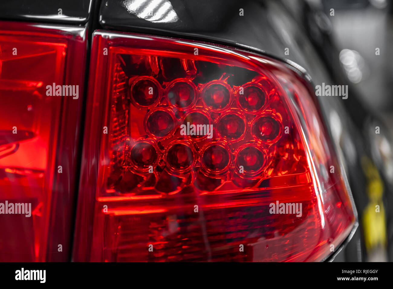 Close-up on the rear LED brake light of red color on a black car in the ...