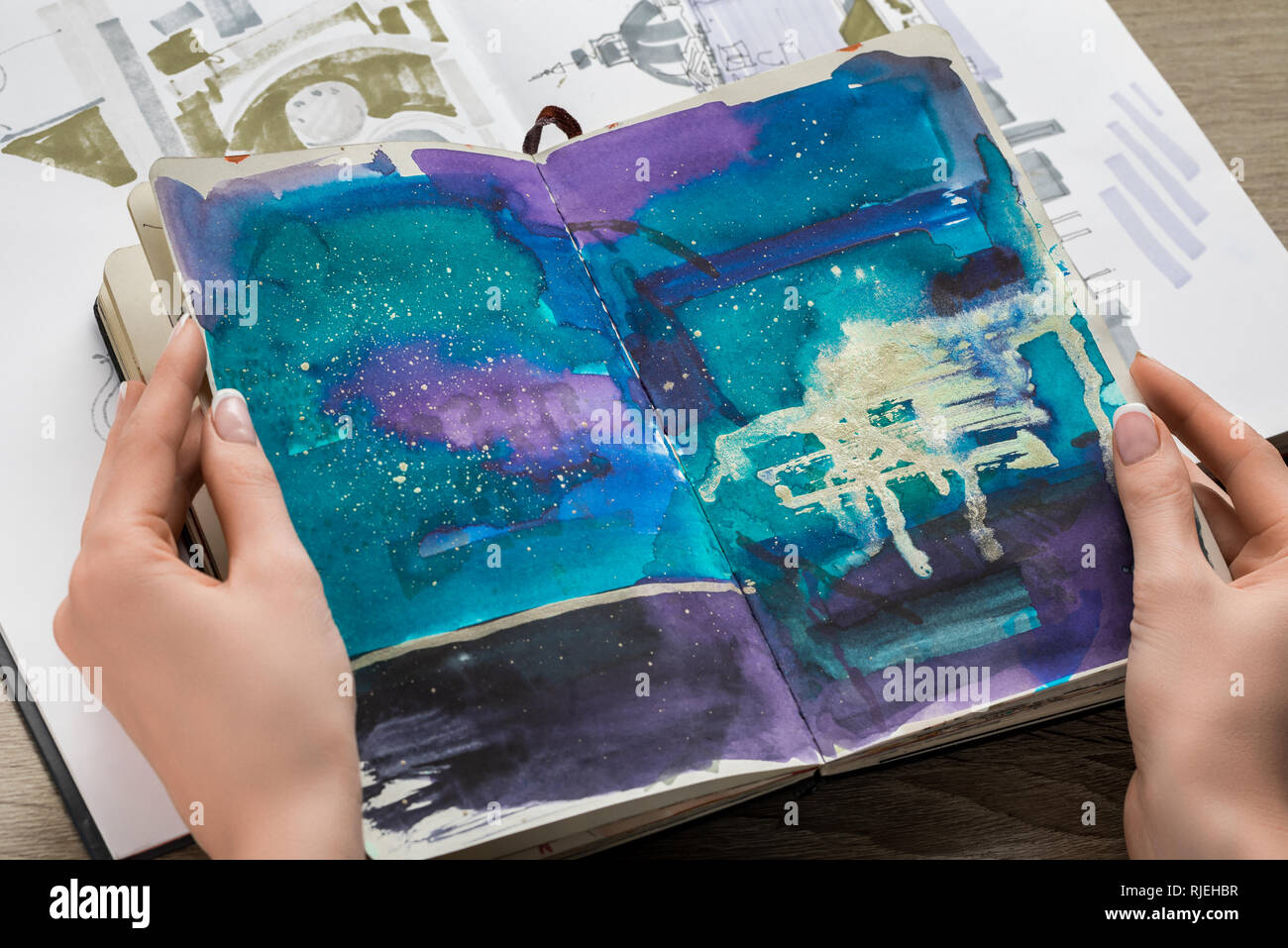 top view of female hands holding notebook with abstract blue drawing ...