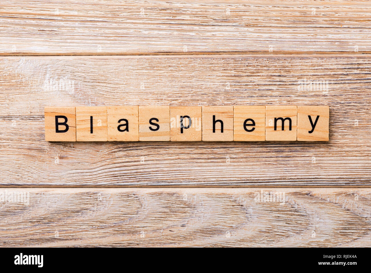 BLASPHEMY word written on wood block. BLASPHEMY text on wooden table ...