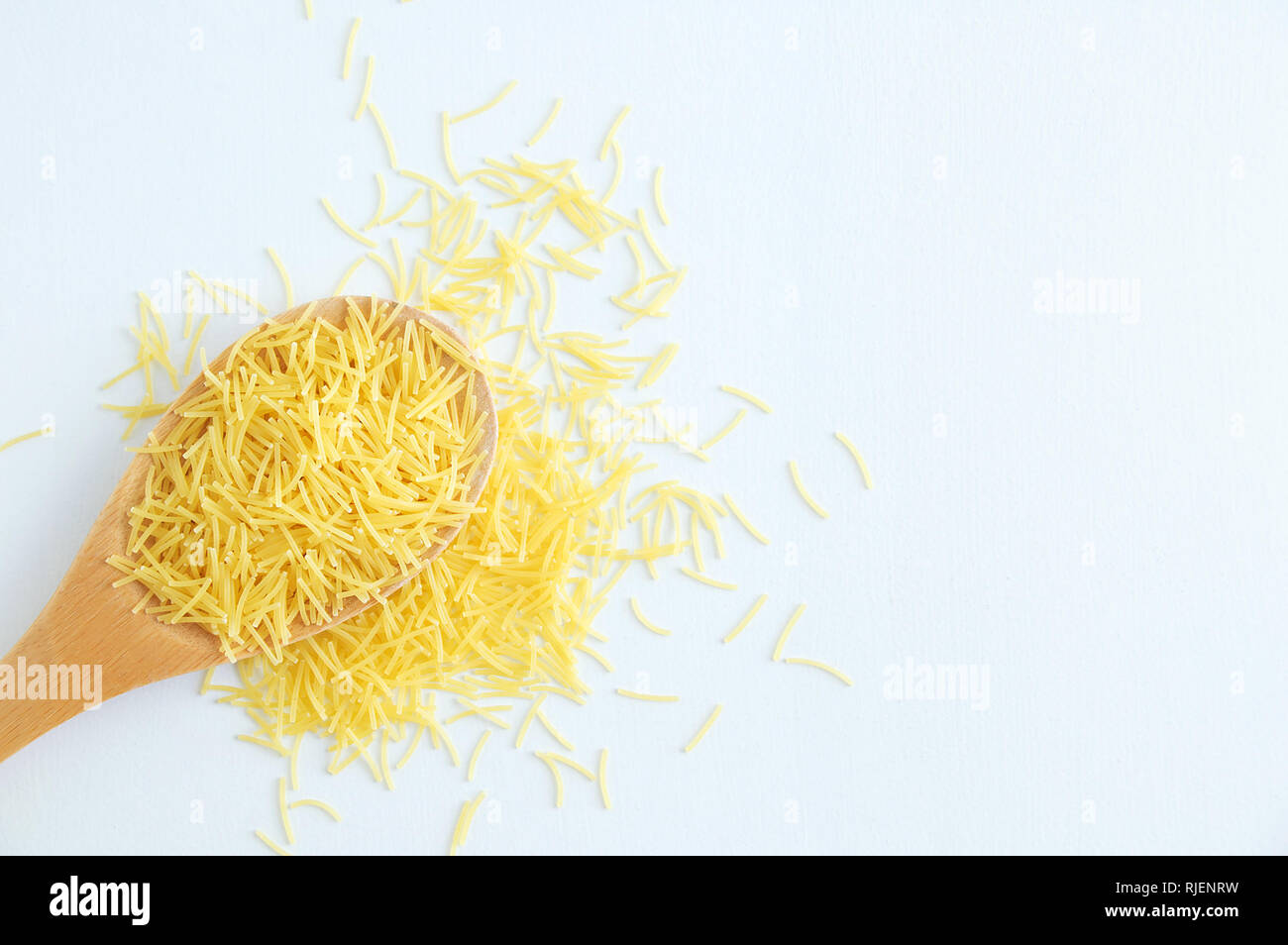 Small noodles on a wooden spoon and scattering. White background Stock ...