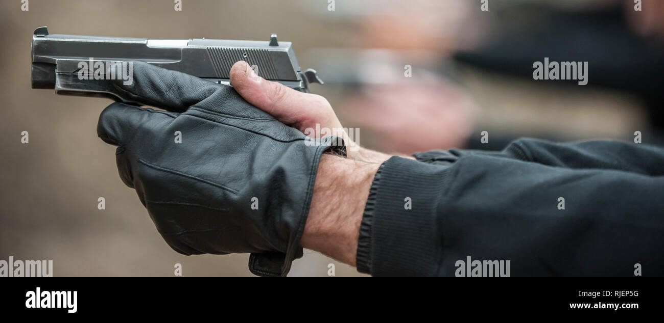 Detail view of shooter in row group of people hold gun and shooting on ...