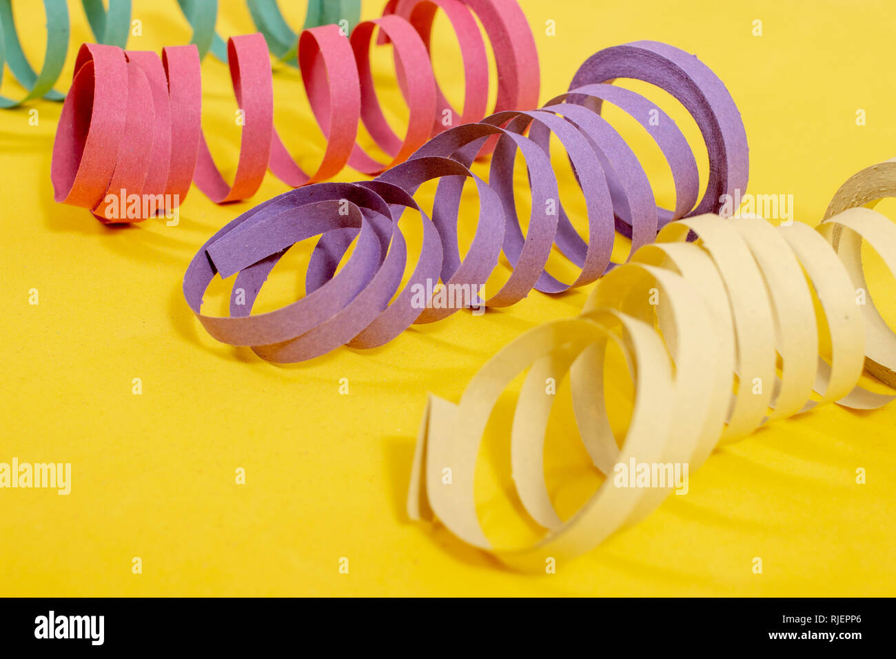 Mixed colorful streamers on a yellow background Stock Photo - Alamy