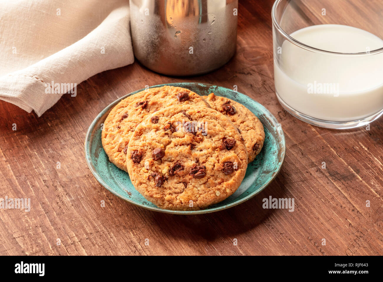 A closeup photo of chocolate chip cookies with milk on a dark rustic ...