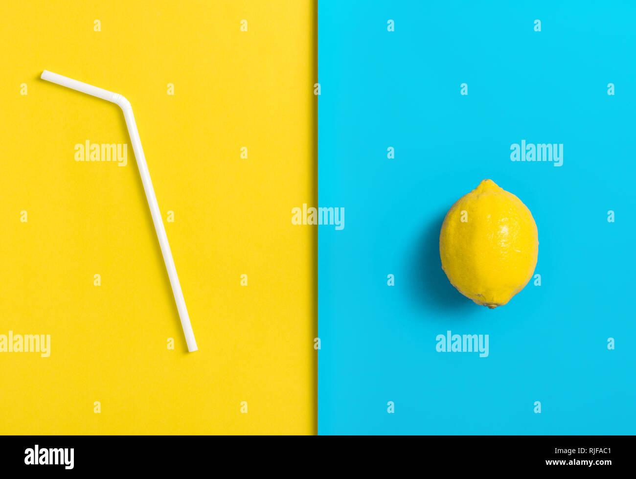 Lemon and straw on split color background Stock Photo - Alamy