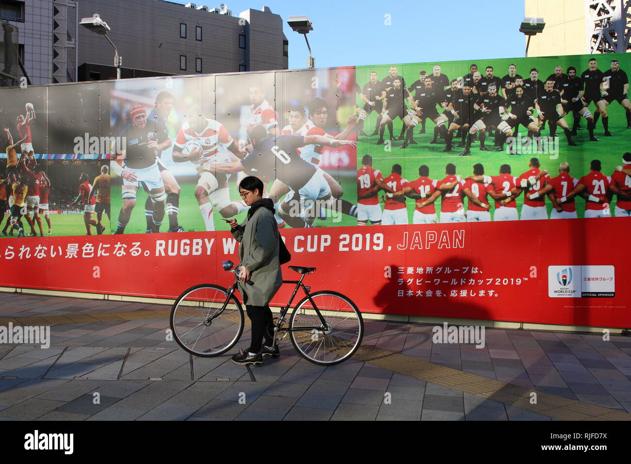 Cyclist on street corner in Tokyo's Gaienmae area with billboard ...