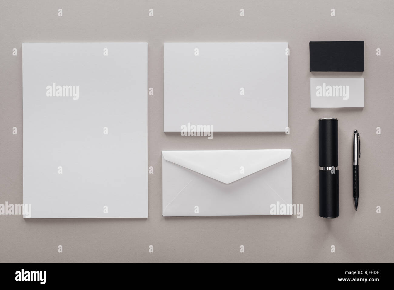 flat lay with blank white papers, envelope and stationery on grey ...