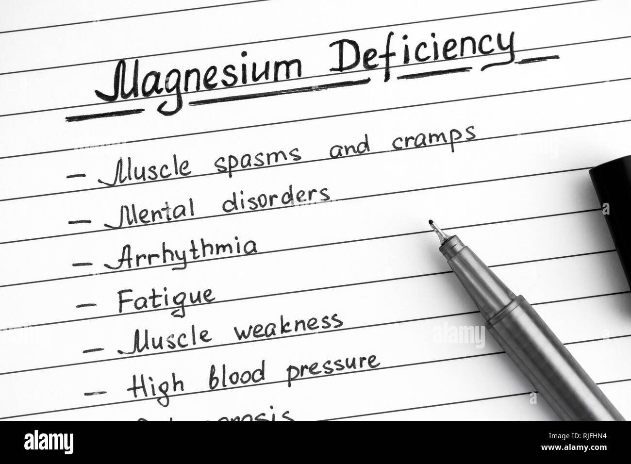 Symptoms of Magnesium Deficiency writing on list with black pen. Close ...