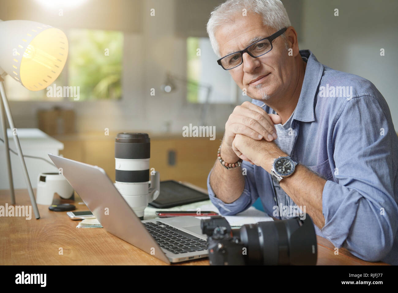 Senior photographer working with laptop hi-res stock photography and ...