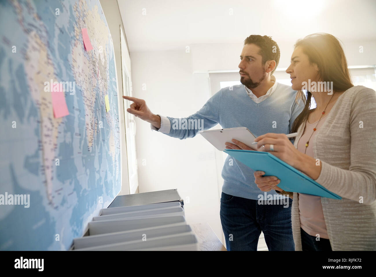 Colleagues in office looking at world map Stock Photo - Alamy