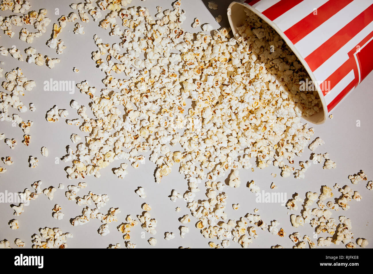 top view of tasty popcorn lying near popcorn cup on white background ...