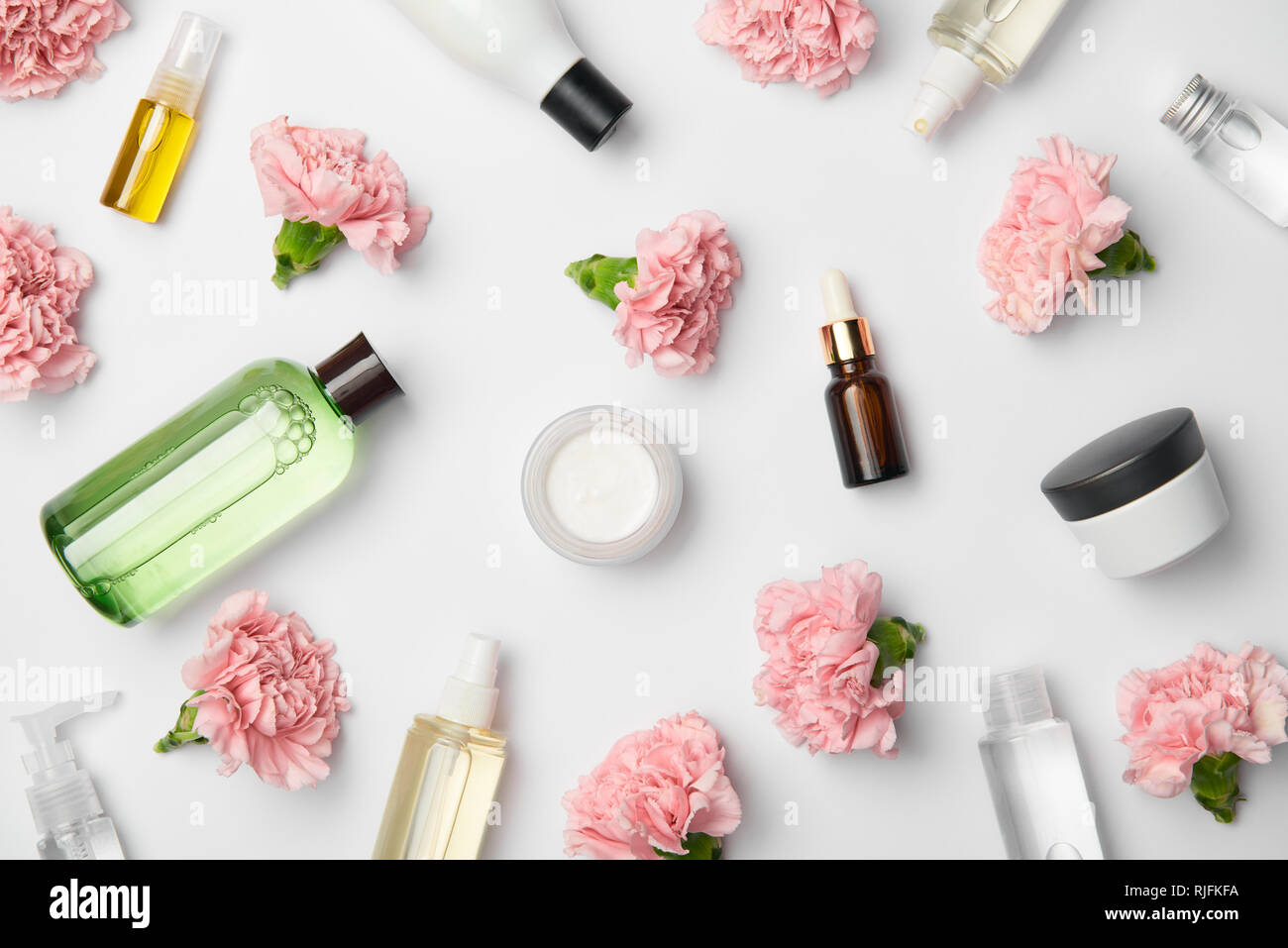 Top view of various cosmetic containers and pink carnations flowers on ...